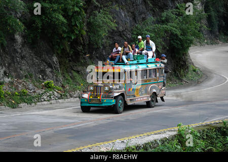 Fully packed Jeepney rides along a curved mountainous road in Isabela ...