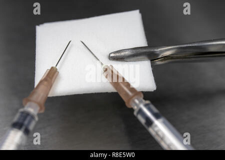 Sterile swab, pliers and a medical syringe on a hospital table ...