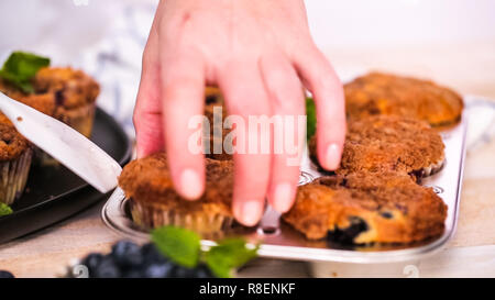 Taking blueberry muffins out of metal muffin pan Stock Photo - Alamy