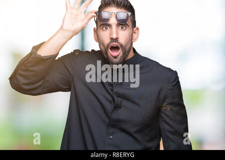 Young Christian priest wearing sunglasses over isolated background ...