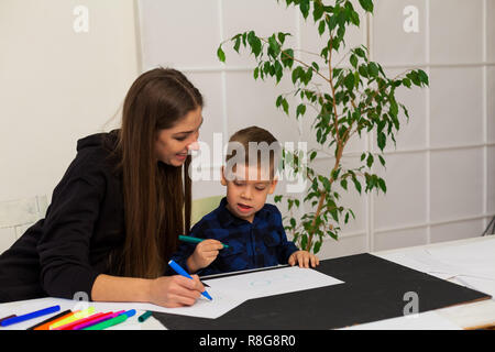 teacher works with small boy paint markers Stock Photo - Alamy