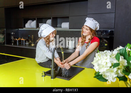 Two girls with chef hat hugging and having fun in kitchen. Sisters ...