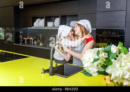 Two girls with chef hat hugging and having fun in kitchen. Sisters ...