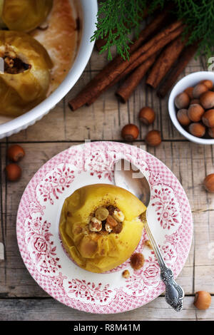 Baked apples with raisins, hazelnuts and cinnamon on wooden background ...
