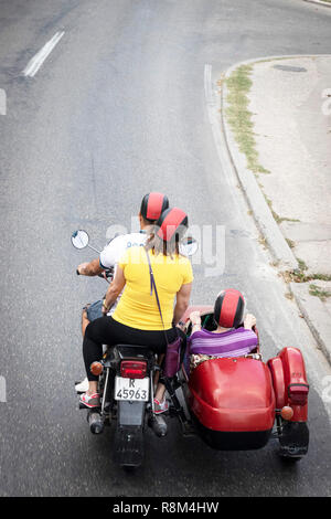 Motorbike with sidecar driving on a road, several vehicles and people ...