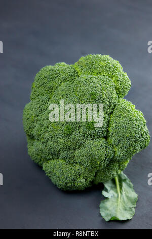 Sliced raw fresh head of broccoli cabbage in a red plate on black ...