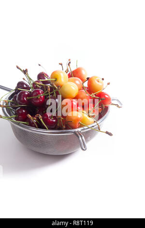 Steel colander with ripe berries of yellow and red sweet cherries on ...