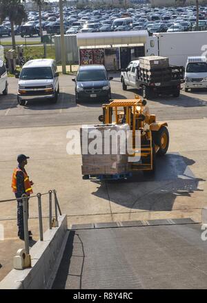 US Navy A Sailor drives his forklift loaded with cargo onto the ...