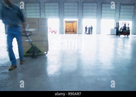Employees loading cardboard boxes of products into truck trailers in a ...