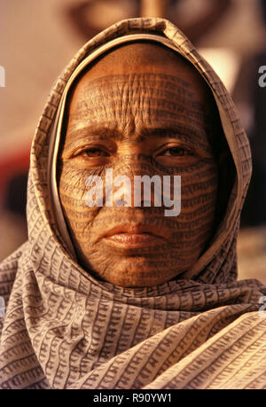 Tattooed face of Ramnaami ascetic woman, against black and white hand ...