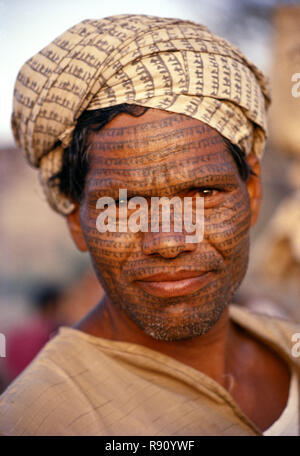 Tattooed face of Ramnaami ascetic woman, against black and white hand ...