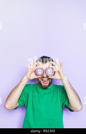 Young bearded holding slices of red onion in front of his eyes ...