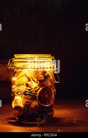 Glass jar with pine cones and garland on dark background. Festive ...