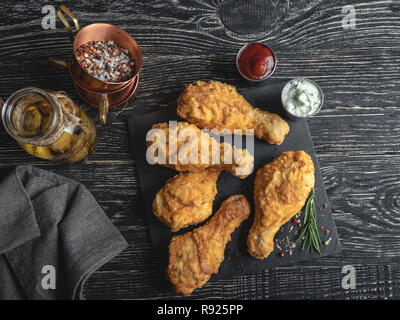 Golden roasted chicken leg on white plate surrounded by green onions ...