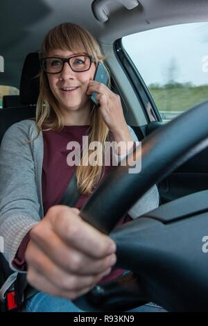 Woman talking on smartphone while driving modern car, view through ...
