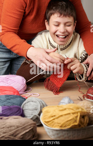 Child boy is learning to knit. Colorful wool yarns are on the wooden ...