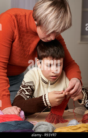 Child boy is learning to knit. Colorful wool yarns are on the wooden ...