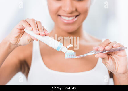 Pretty young girl putting toothpaste on electric brush. Happy woman ...