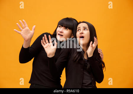 A portrait of a scared mother and daughter at studio on gold background ...