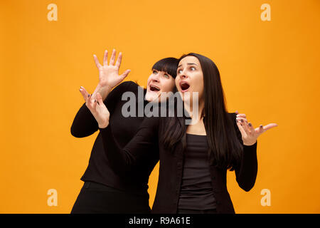 A portrait of a scared mother and daughter at studio on gold background ...