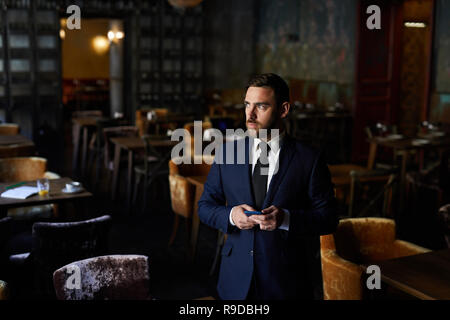 Young pensive owner of cafe in formalwear and eyeglasses searching in ...