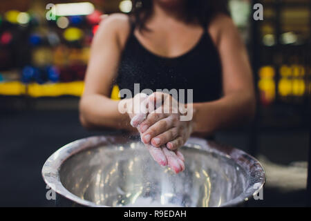 female athlete clapping hands with chalk powder before strength ...