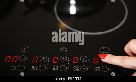 Female finger operating electric stove, nicely manicured finger nails ...