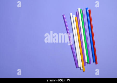 Different plastic straws on purple background Stock Photo - Alamy