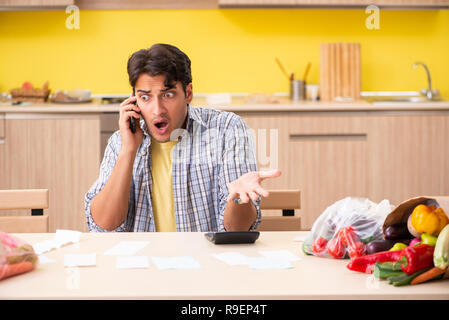 Young man calculating expences for vegetables in kitchen Stock Photo ...