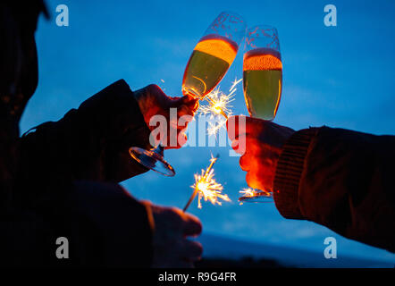 hands of elderly couple holding sparkles and glasses of champagne ...
