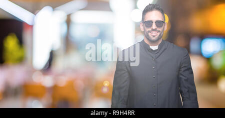 Young Christian priest wearing sunglasses over isolated background ...