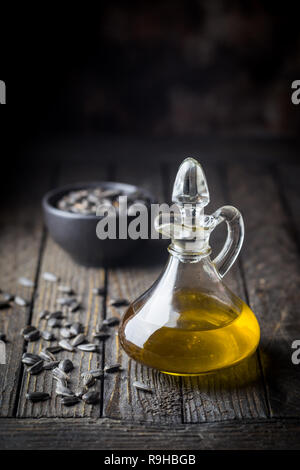 Jug of oil, sunflower and jar with seeds on brown background Stock ...