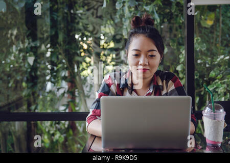 Young asia woman sitting alone and working on a laptop at coffee shop ...