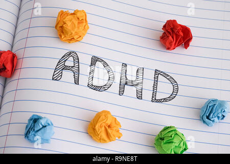 ADHD. Abbreviation ADHD on notebook sheet with some crumpled paper ...