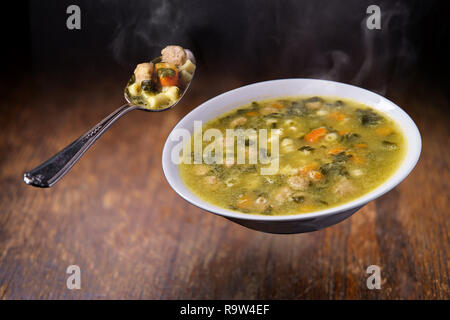 Bowl of hot steamy Italian wedding soup floats in the air above rustic ...