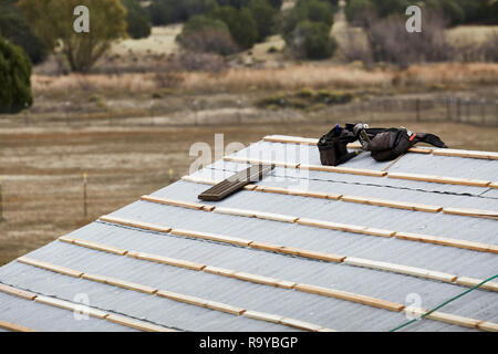 Wooden slats laying on rooftop with tool belt and clay tile in ...