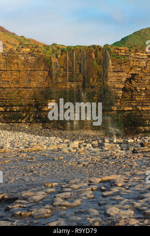 Small waterfall off rocky cliff with snow and ice, Seljalandsfoss area ...