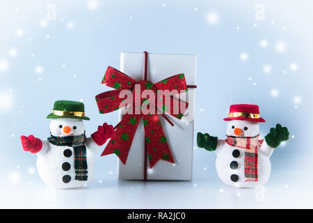 Snowman stand near gift box on white background. Snow flake is falling ...