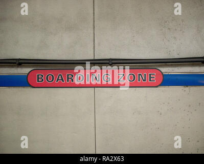 BOARDING ZONE in black and red on tile wall split between tan and white ...