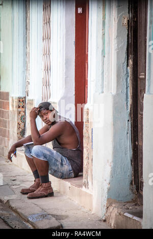 handsome young cuban man in black attire posing with hands in pockets ...