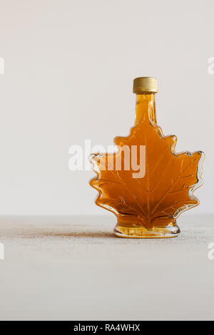 maple syrup in a leaf shaped glass bottle photographed on a white ...