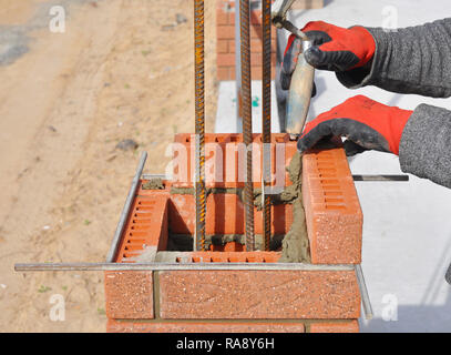 Bricklayer hand laying brick column with metal rod Stock Photo - Alamy