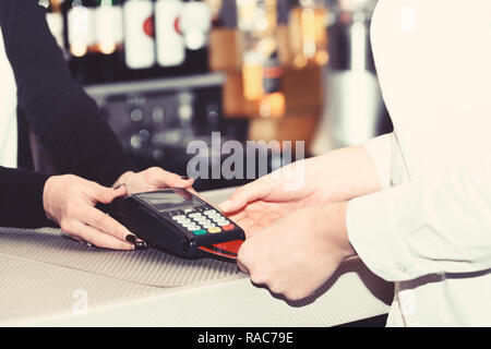 Cashiers hand holds credit card terminal on defocused background Stock ...