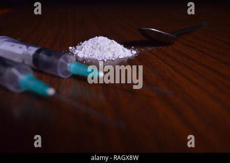 Narcotics being prepared. Needles, spoon and white powder on a table ...