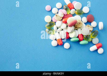Pills are scattered over a blue background Stock Photo - Alamy