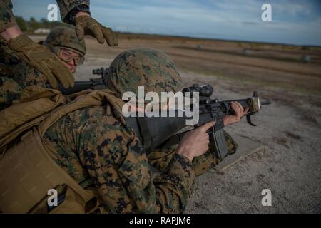 A Marine is corrected on his firing position and prone stance by a ...