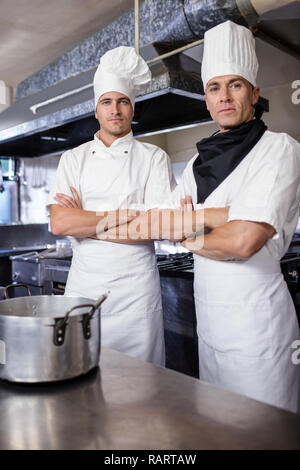 Two male chefs standing with arms crossed in kitchen Stock Photo - Alamy