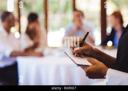Waitress writing ordering on notepad, partial view Stock Photo - Alamy