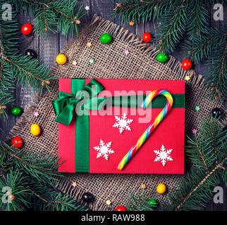 Gift box with yellow bow, candy cane and cones with fir branches on ...