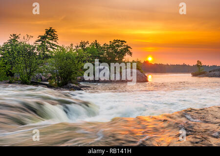 A beautiful sunrise at Burleigh Falls Ontario shows a starburst pattern ...